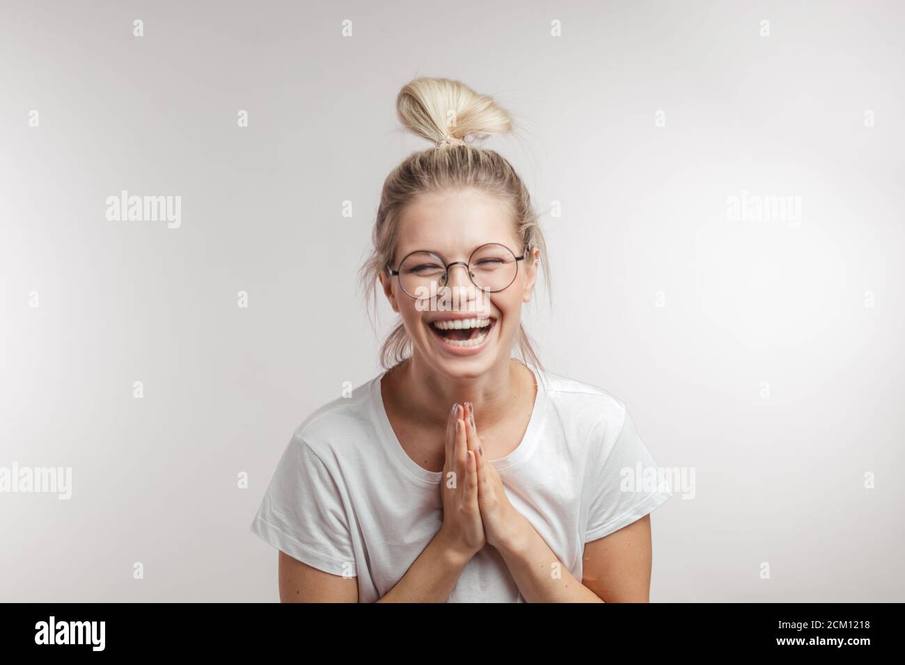 Joyful blonde young woman wearing stylish hair knot and spectacles ...