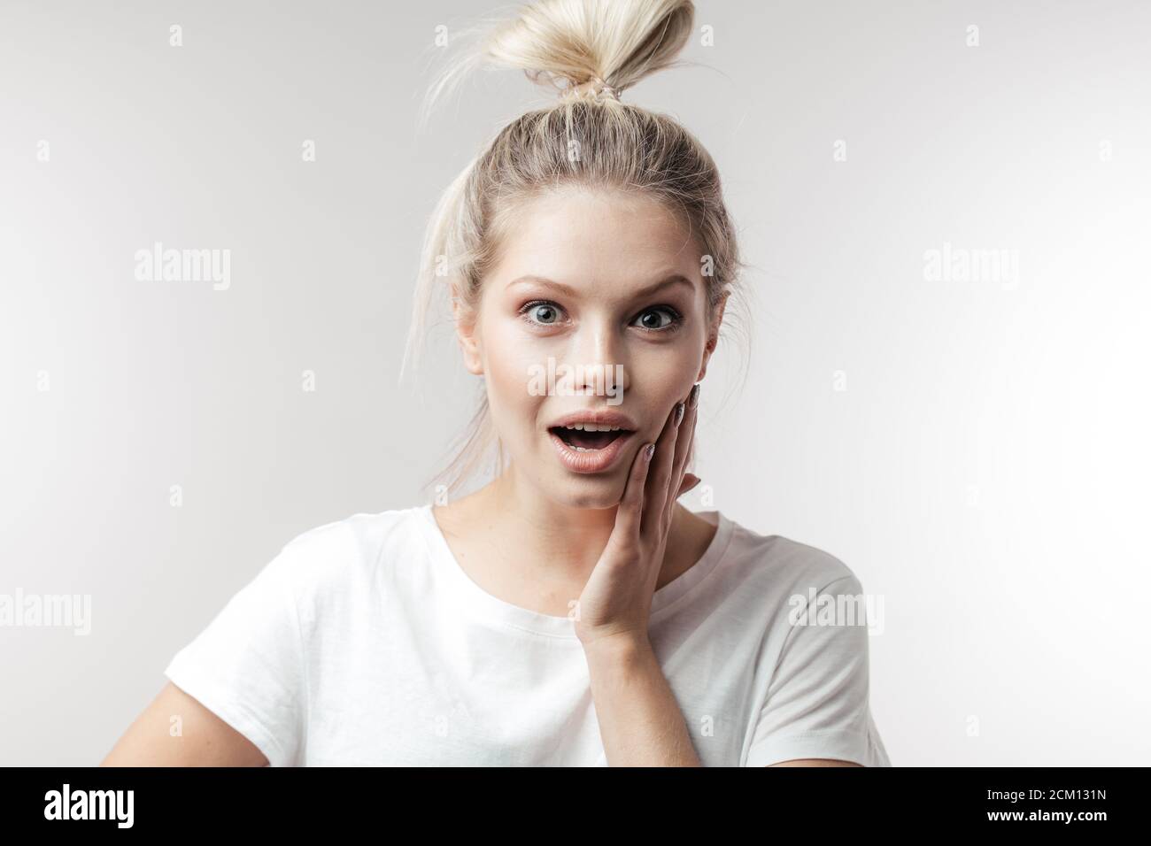 Excited young caucasian woman looks with surprised amazed expression ...