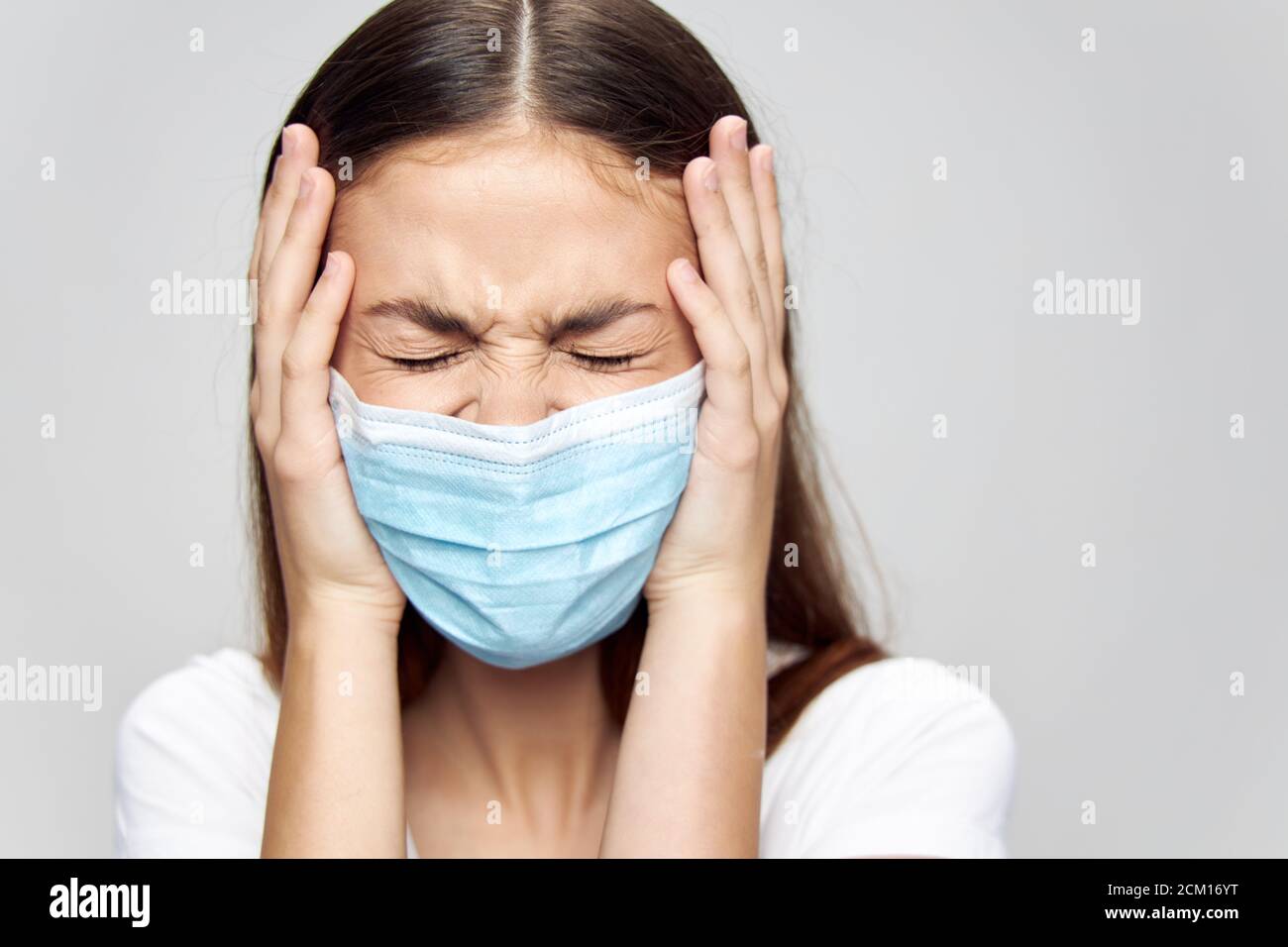 Irritable woman in medical mask squinting her eyes and touching her ...
