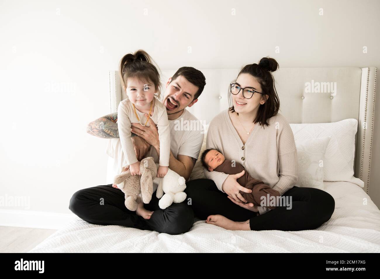 Modern Millennial Family With Toddler and Newborn Plays on White Bed ...