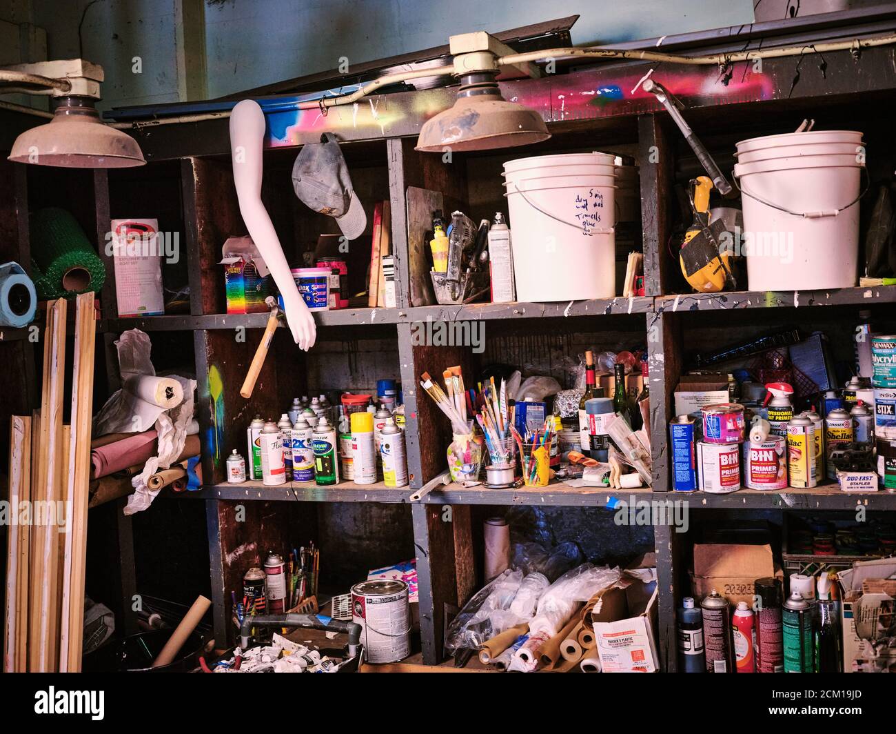 Shelves in an artists studio packed with clutter supplies and material ...