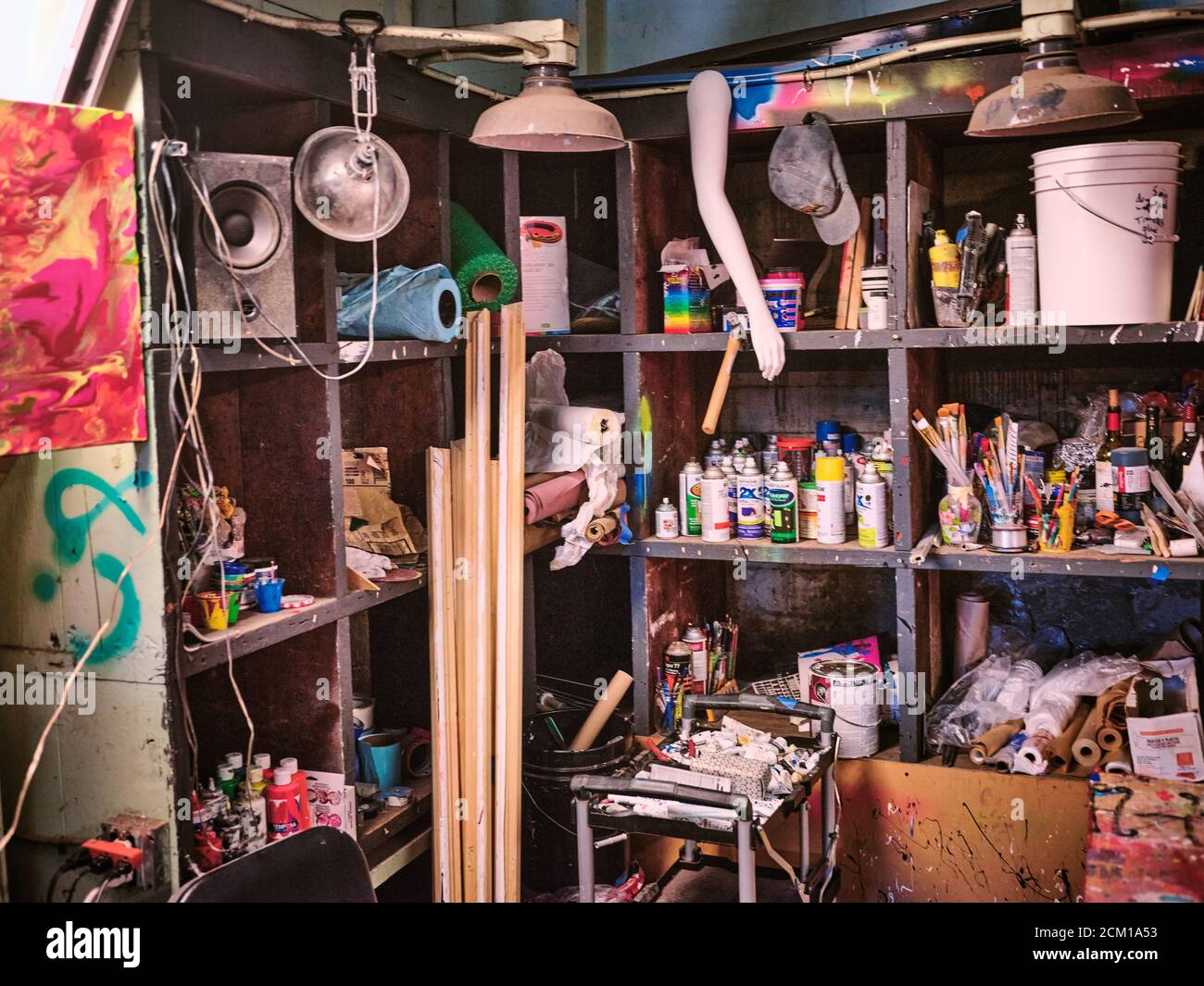 Shelves in an artists studio packed with clutter supplies and material ...