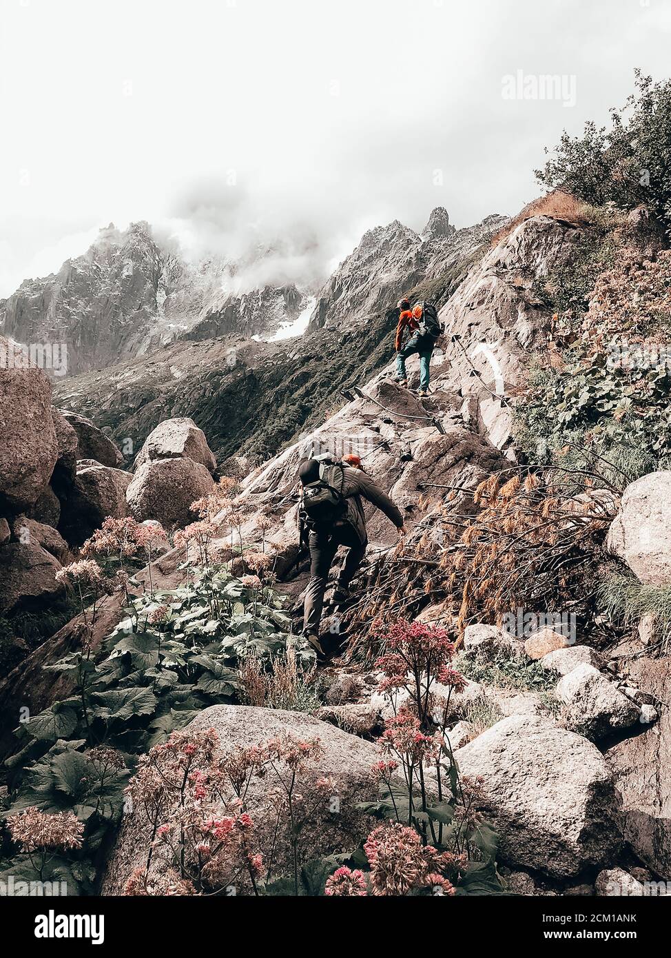 Two Climbers scrambling over rocks towards big faces Stock Photo - Alamy