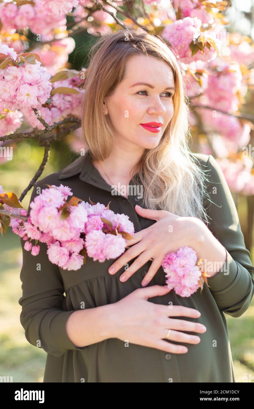 Freckled Blonde Pregnant Woman In The Park At Spring With Sakura Trees Shallow Depth Of Field