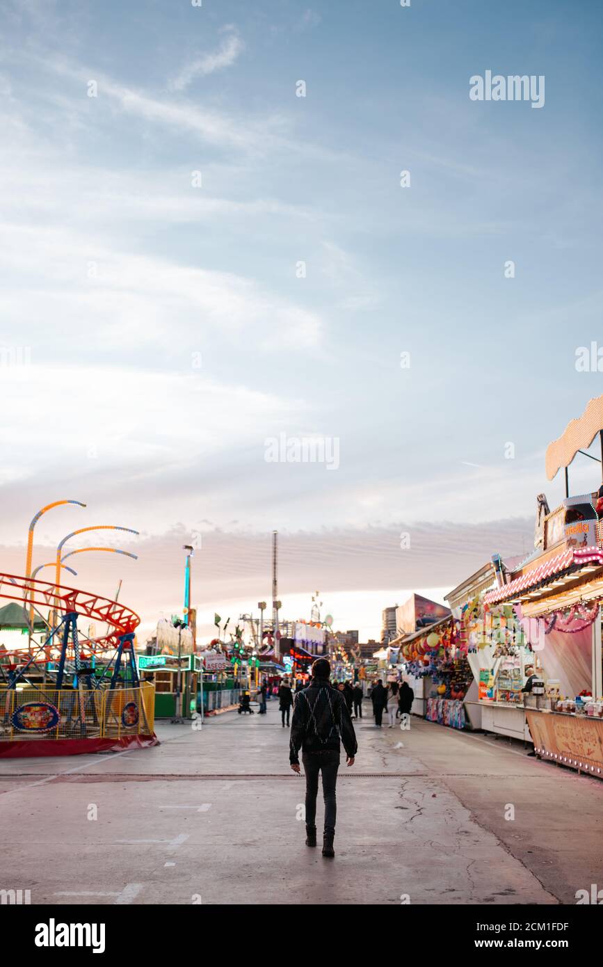 Young man in a colorful funfair/amusement park at sunset Stock Photo ...