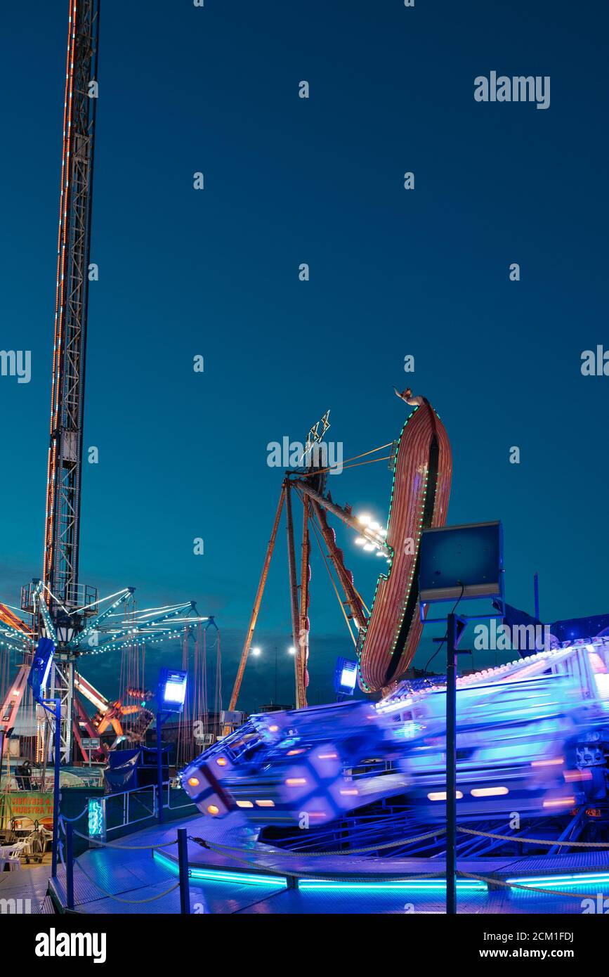Colorful funfair pirate boat ride and ferries wheel at dusk Stock Photo ...