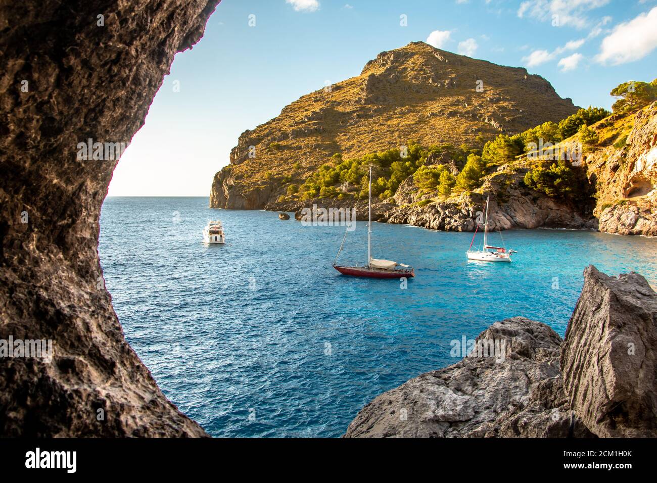 Stunning Sa Calobra beach view from a cave with luxury boats at sunset ...