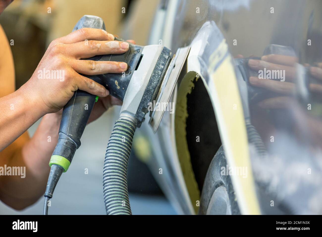 Grinder in the hands of a man who sharpen a car varnish in the car shop ...