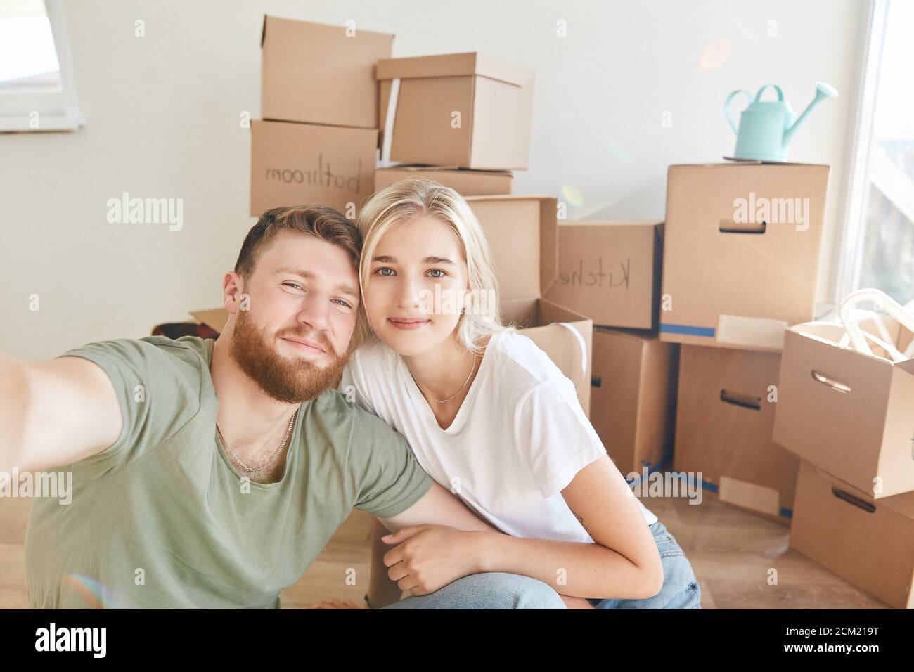 young couple is moving, making selfie, smiling while sitting among ...