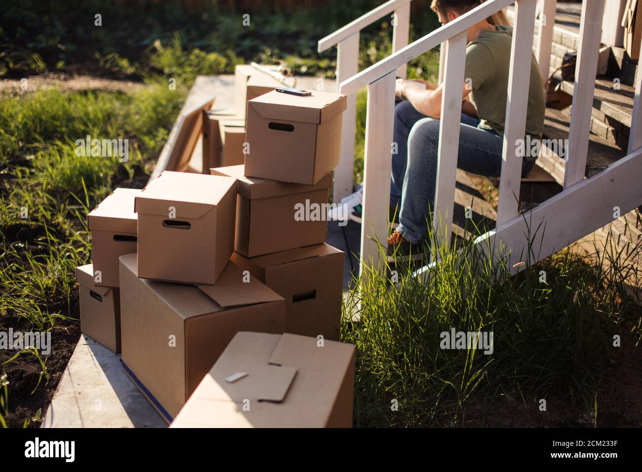 Family Outside House On Moving Day. cardboard boxes foreground near ...