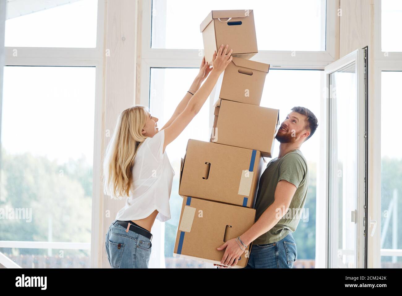 blonde female placing moving boxes on large stack man is holding all ...