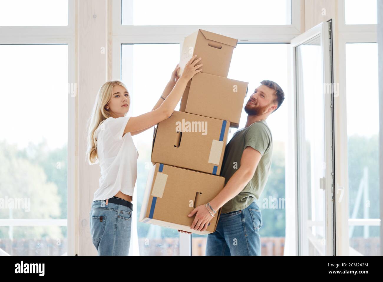 blonde female placing moving boxes on large stack man is holding all ...
