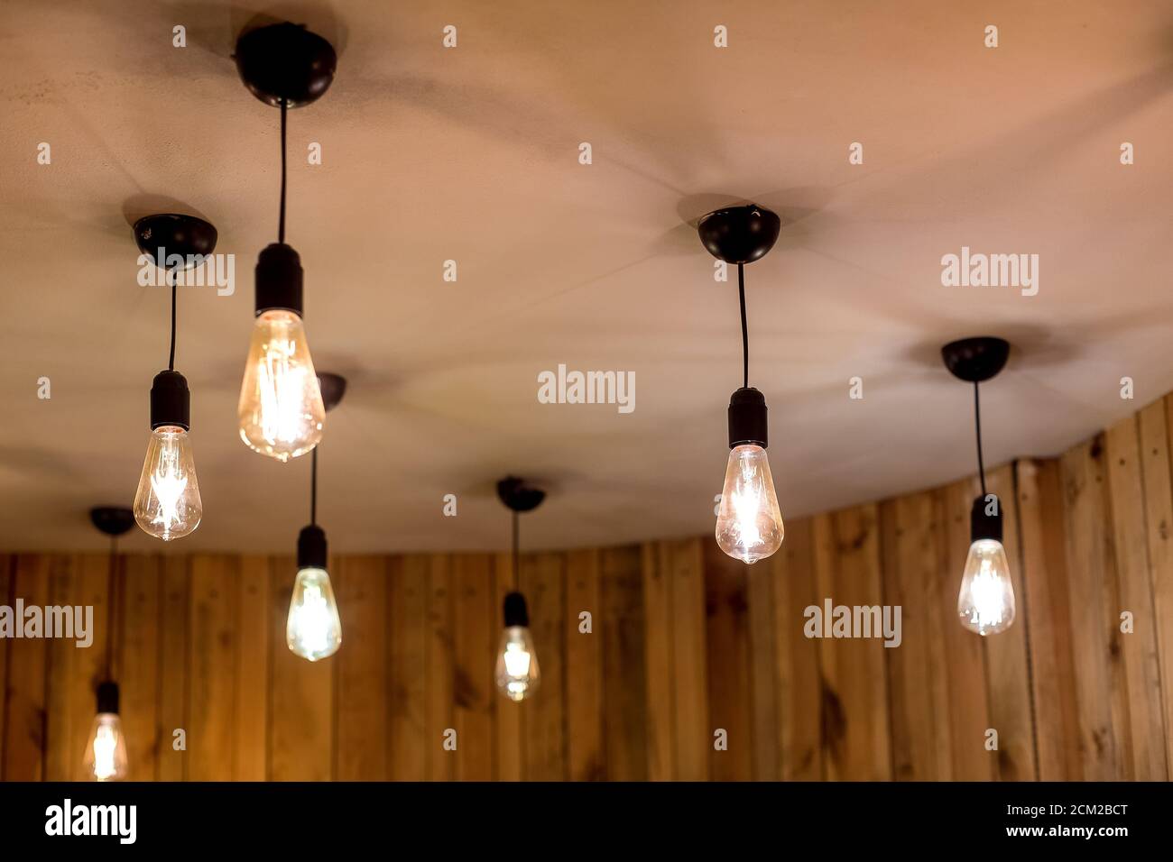 many edison bulbs hanging on a white ceiling in a room with wooden ...