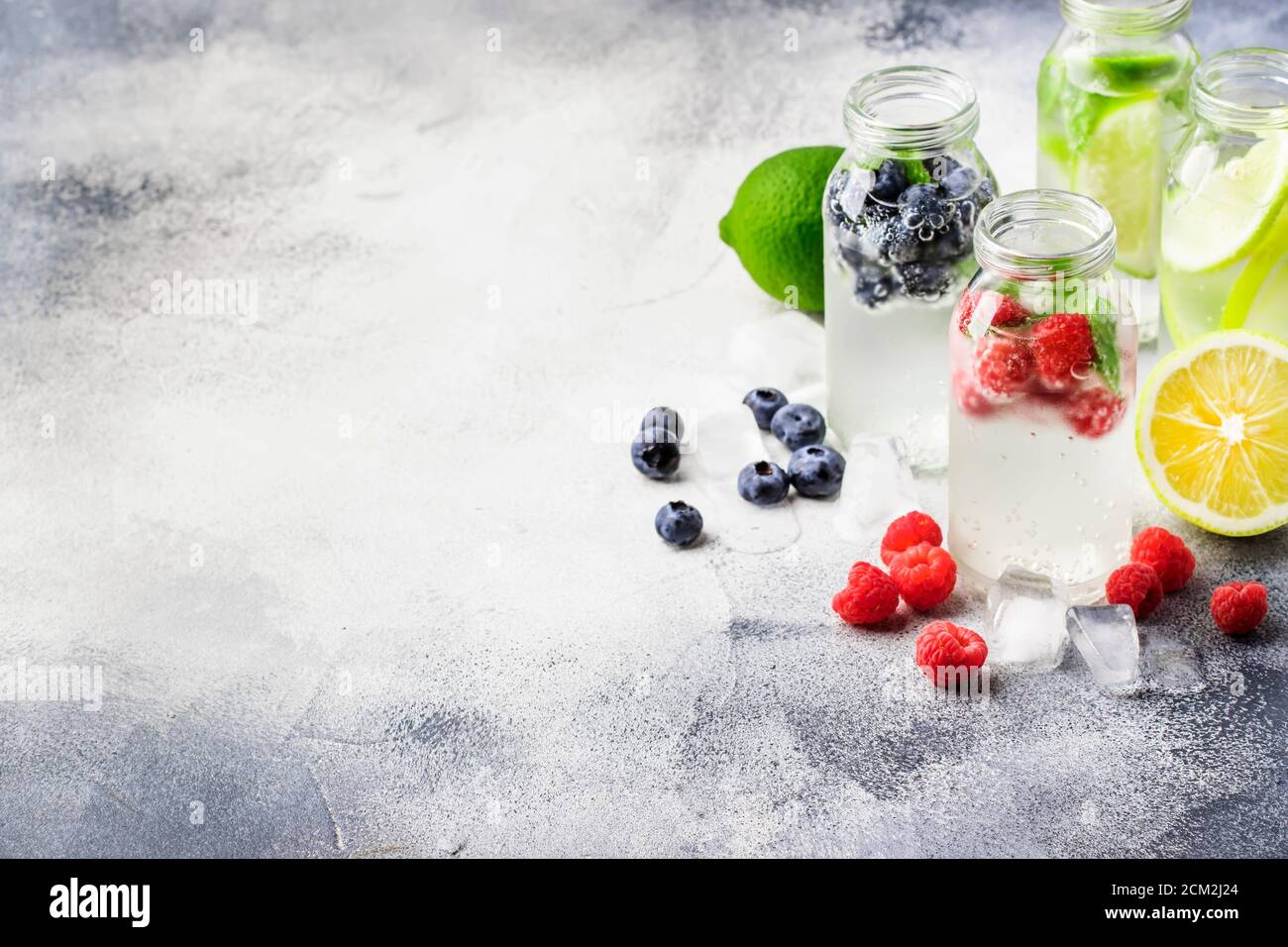 Berry and citrus soft drinks and cocktails in glass bottles on gray ...