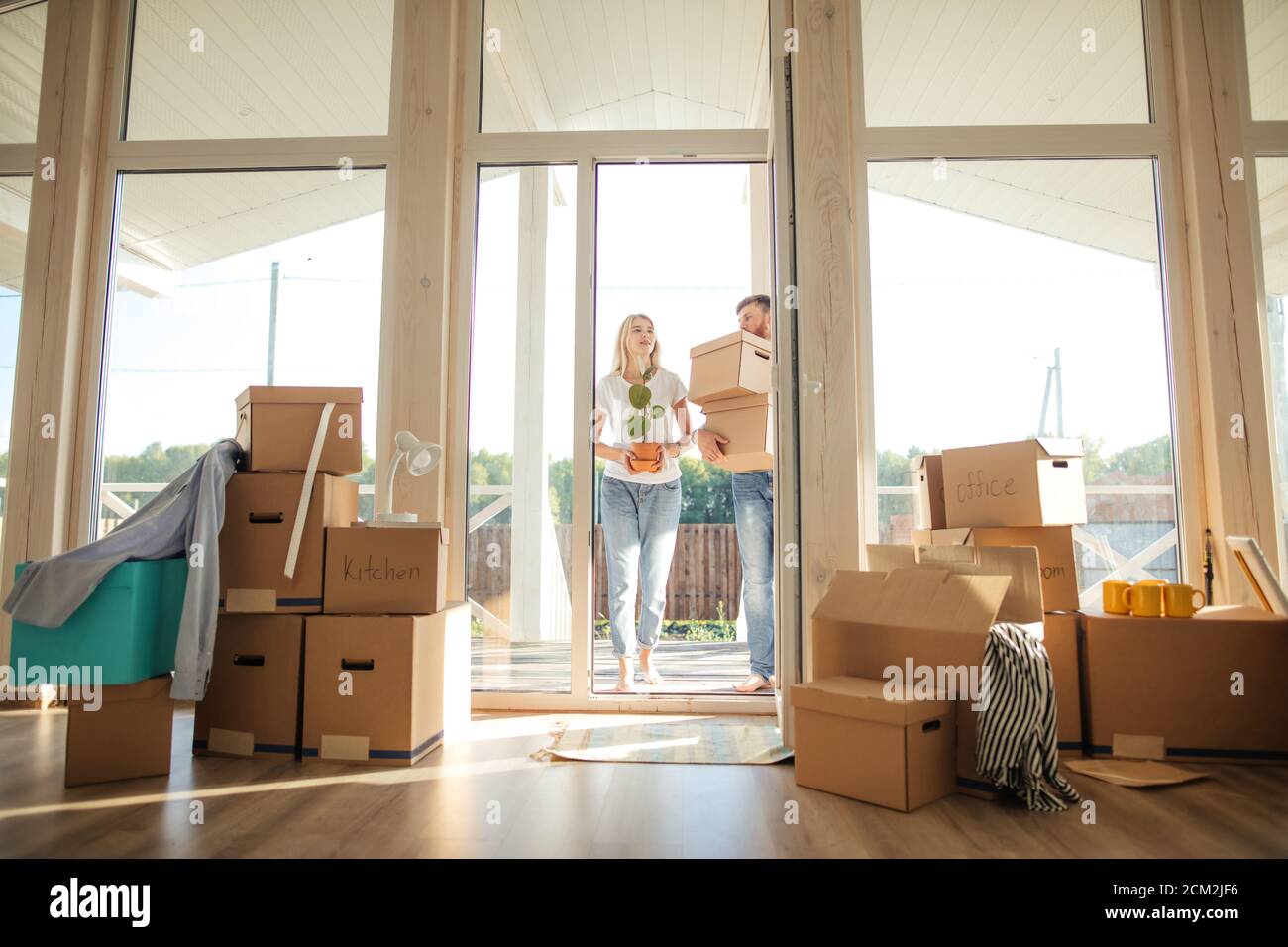 Moving to new home. Happy couple holding cardboard boxes while going ...