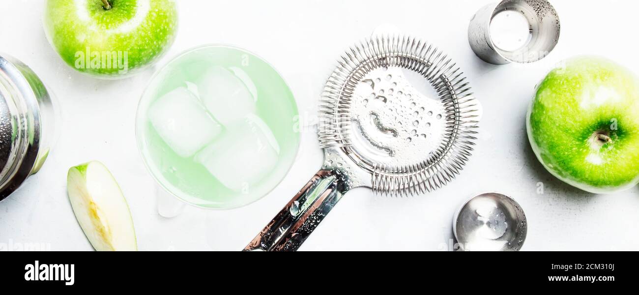 Summer alcoholic cocktail with green apple, vermouth and ice, bar tools ...