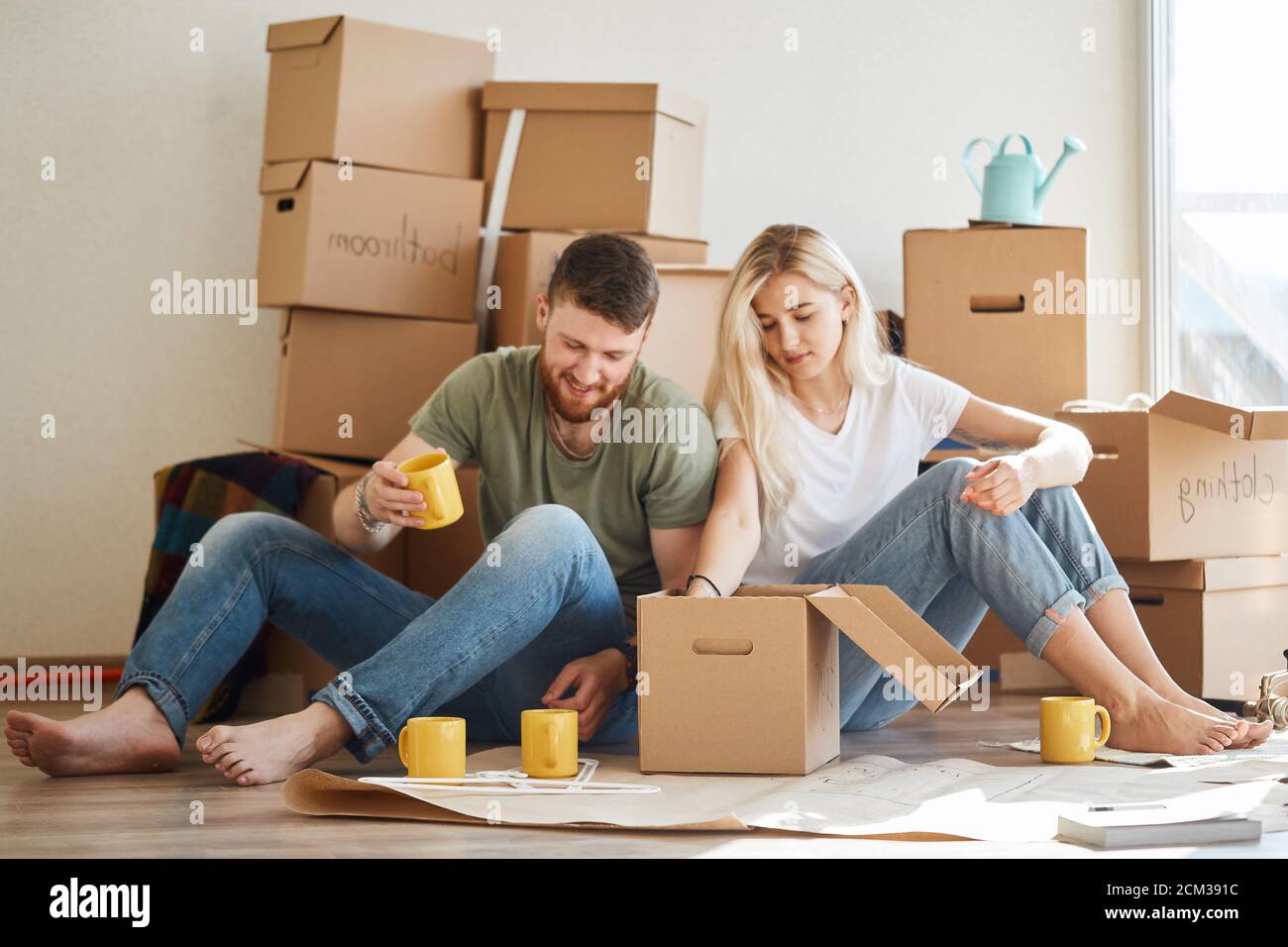Young couple unpacking cardboard boxes at new home. Moving house Stock ...