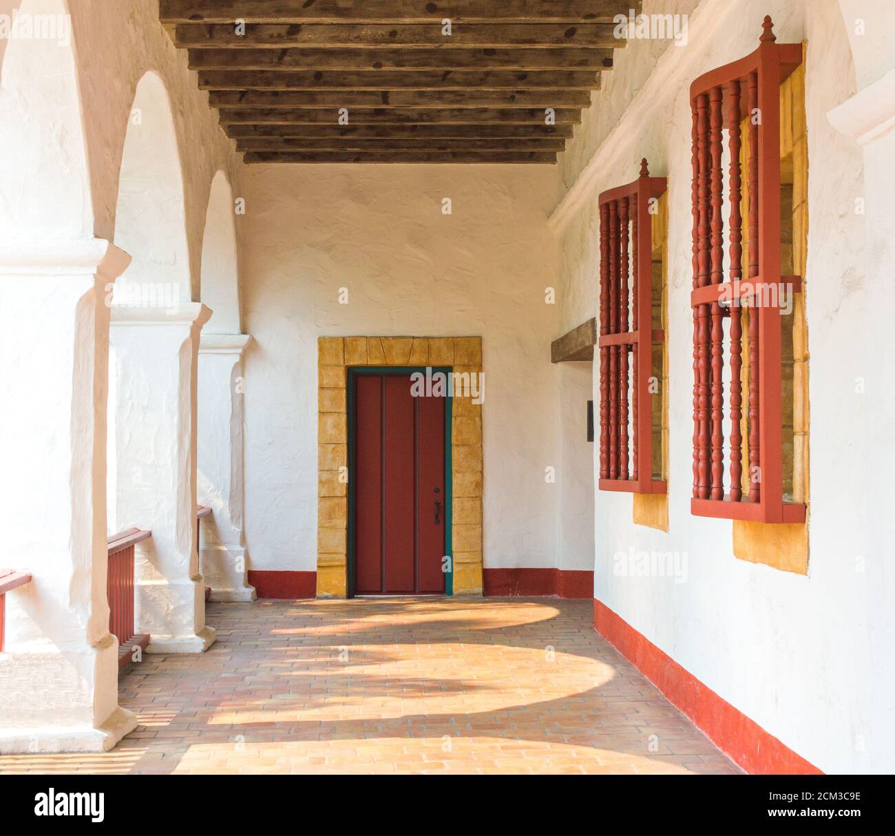 beautiful arched outdoor walkway leading to a vintage red door at the ...
