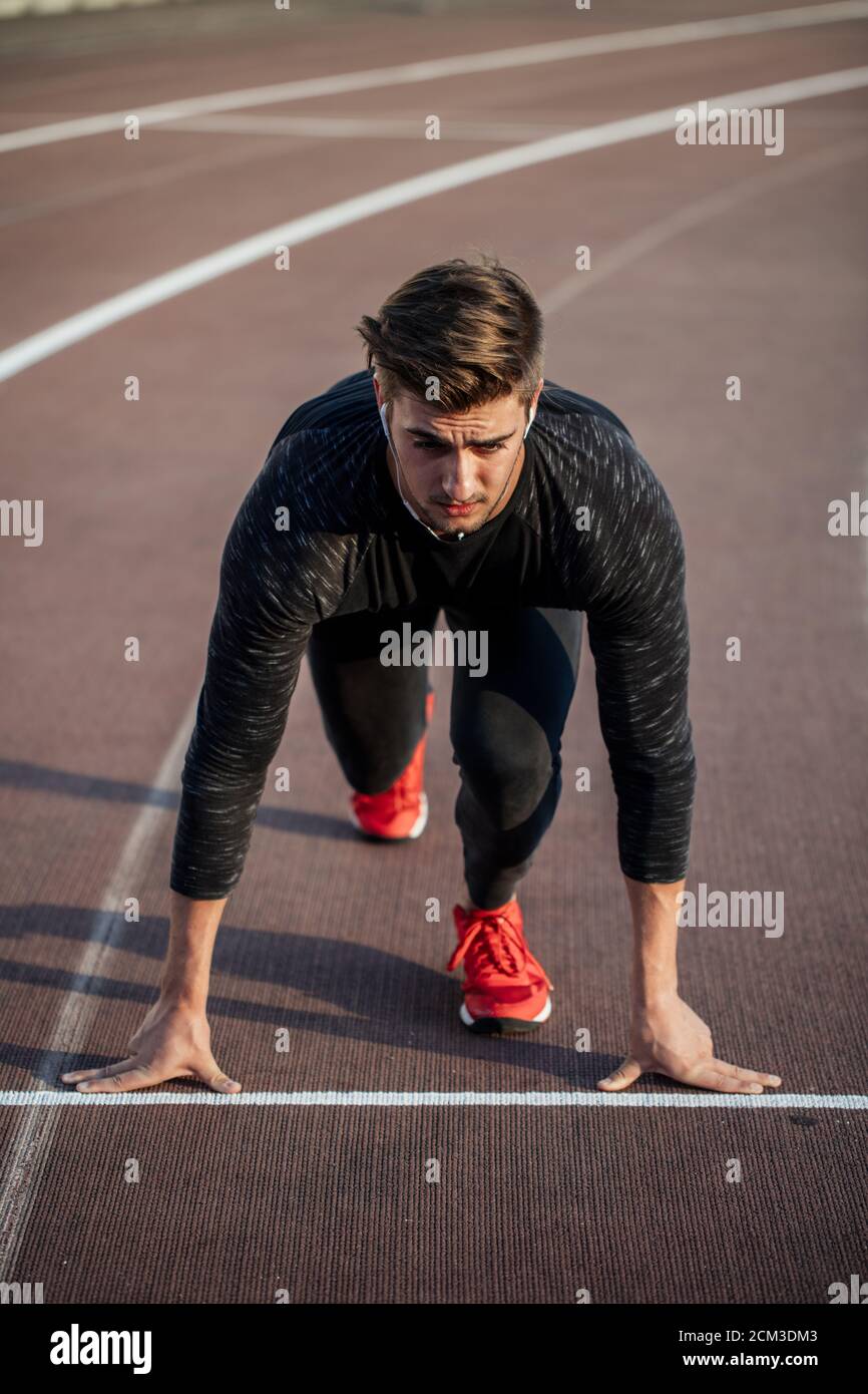 Male athlete on starting position at running track. Runner practicing ...