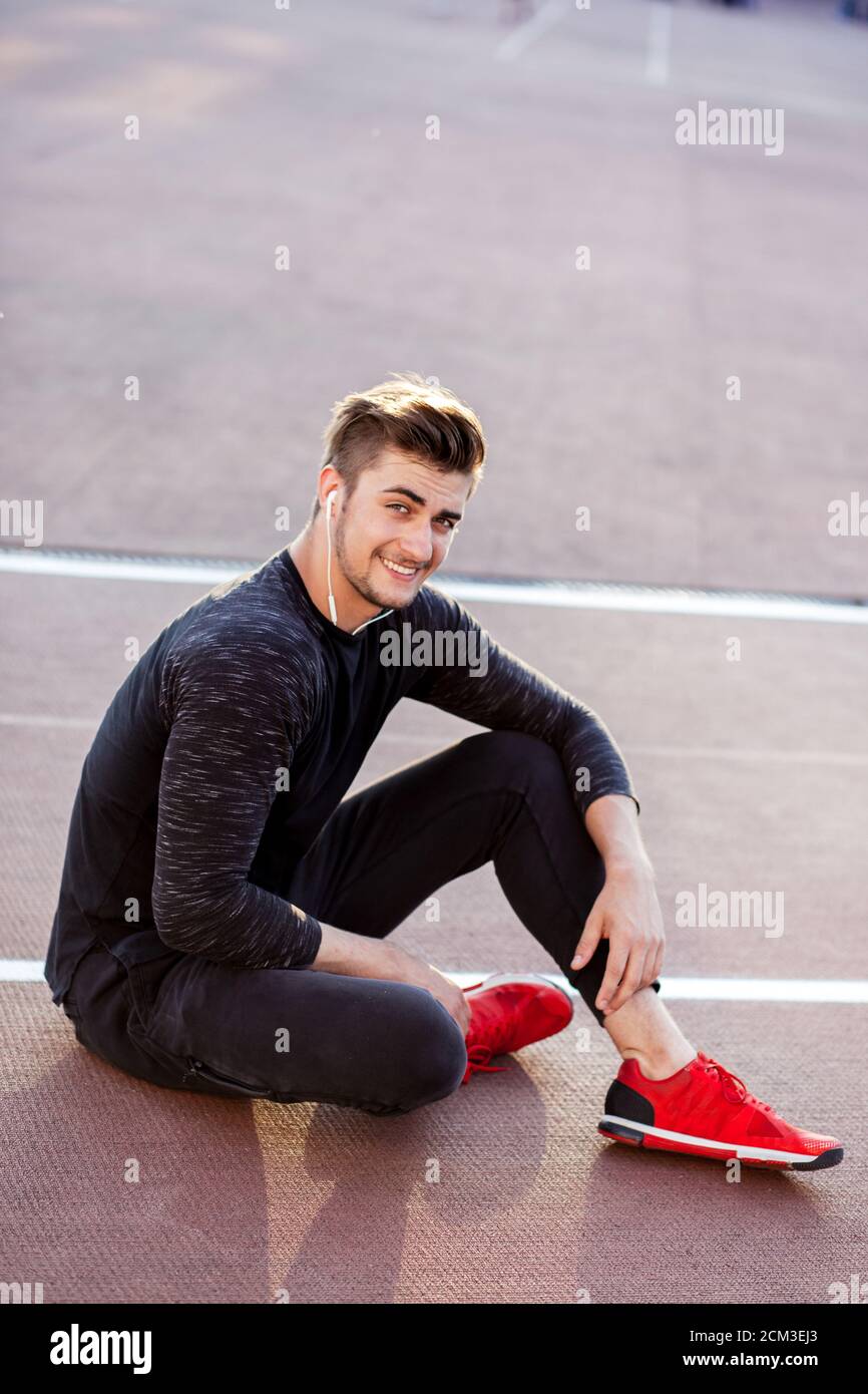 time to rest. young man resting after running on track in stadium Stock ...