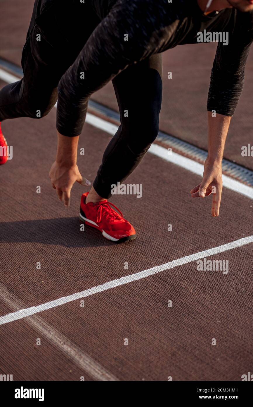 Male athlete on starting position at running track. Runner practicing ...