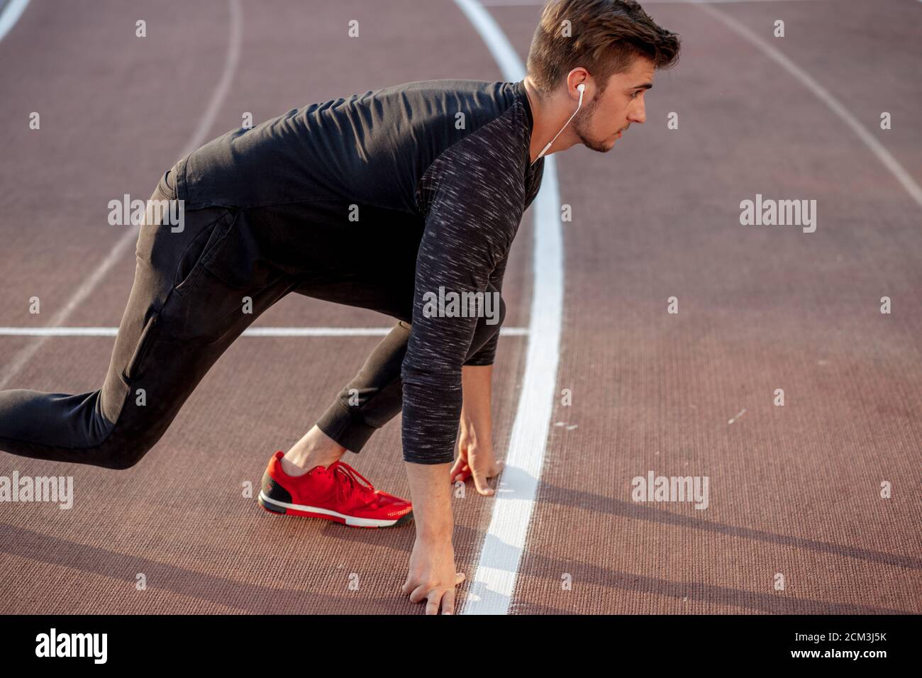 Male athlete on starting position at running track. Runner practicing ...