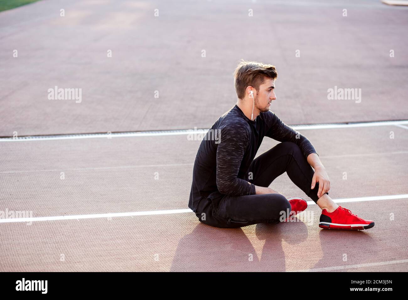 man sitting on race track and rest after jogging Stock Photo - Alamy