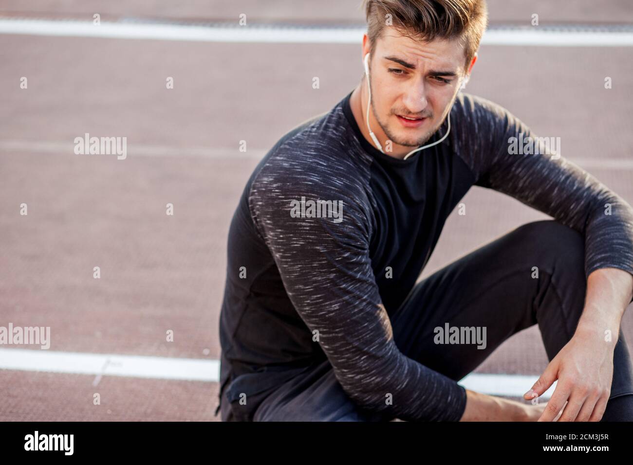man sitting on race track and rest after jogging Stock Photo - Alamy