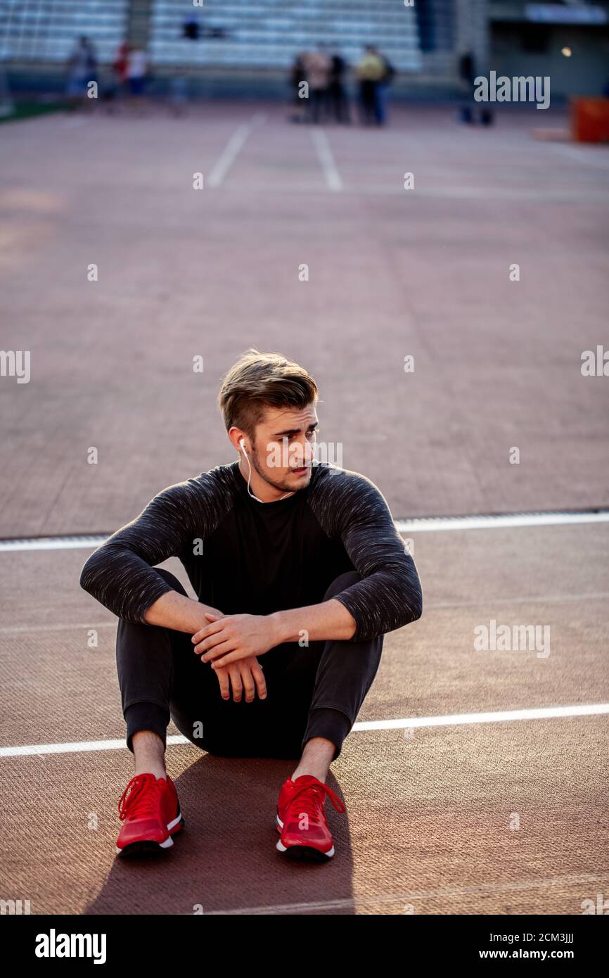 man sitting on race track and rest after jogging Stock Photo - Alamy