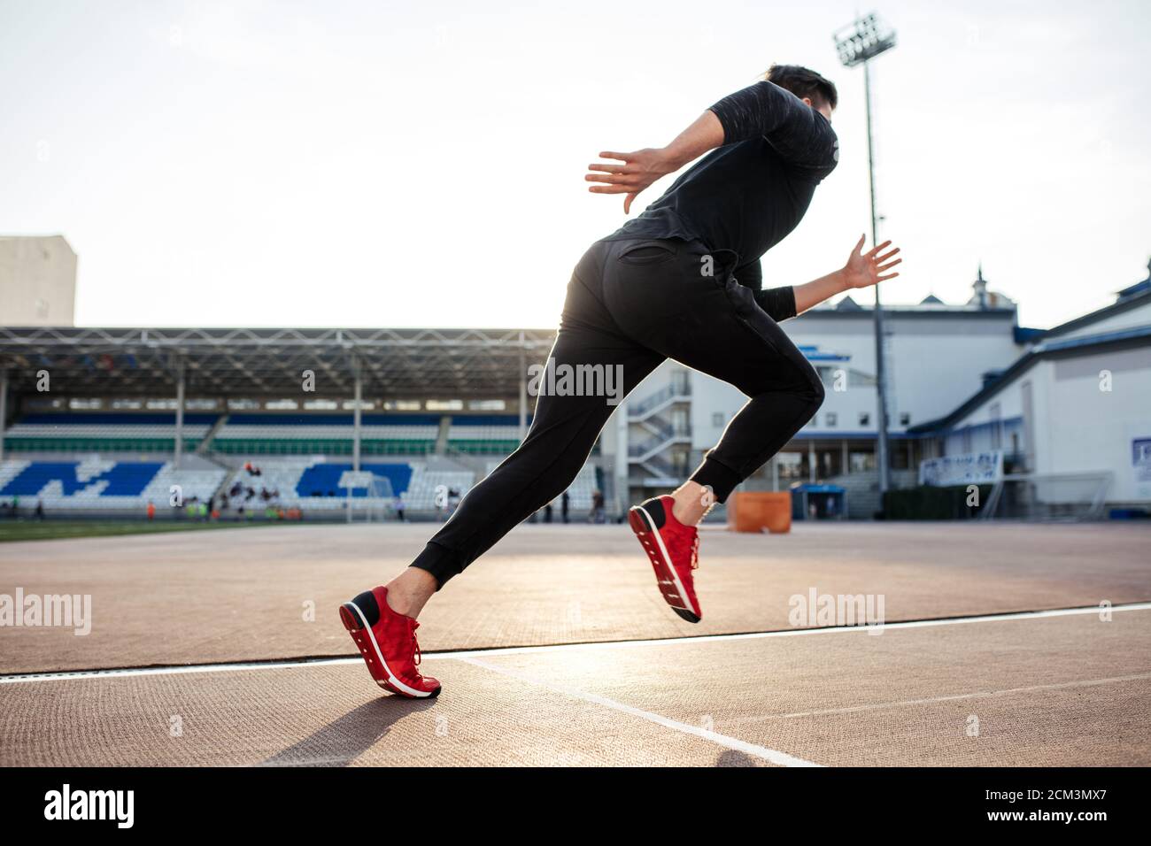 Male athlete in black clothes starting sprint on running track Stock ...