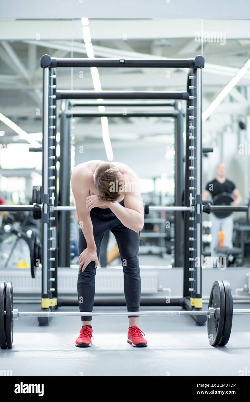 Caucasian muscular man putting heavy plates on barbell during workout ...