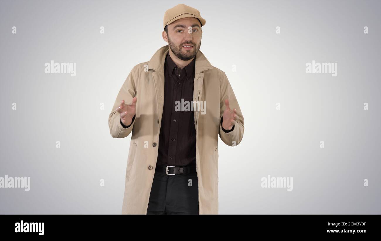 Charming man in trench coat walking and talking to camera on gra Stock ...
