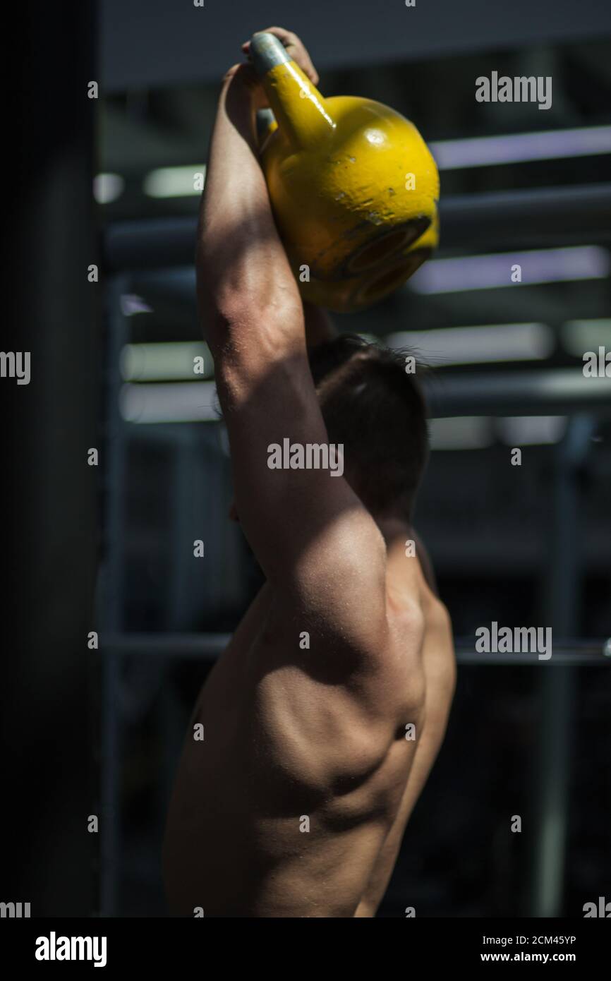 Handsome bodybuilder pumping up muscular body, doing exercises in gym ...