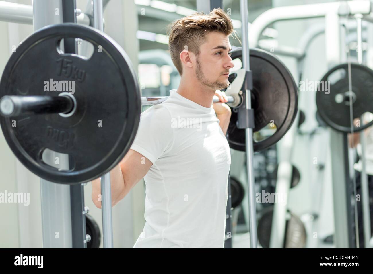 Professional athlete near barbell machine and is preparing to lift a ...