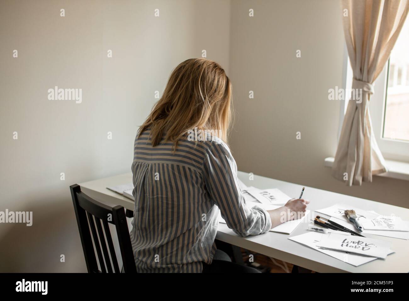 Back rear view Portrait of young beautiful lady sitting at white desk ...