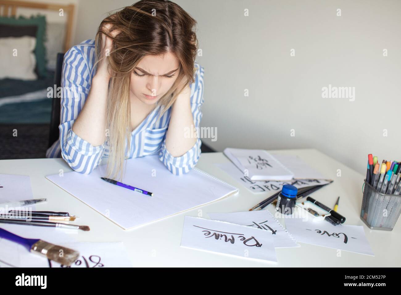 Tired sad calligraphy female artist sitting at desk Stock Photo - Alamy