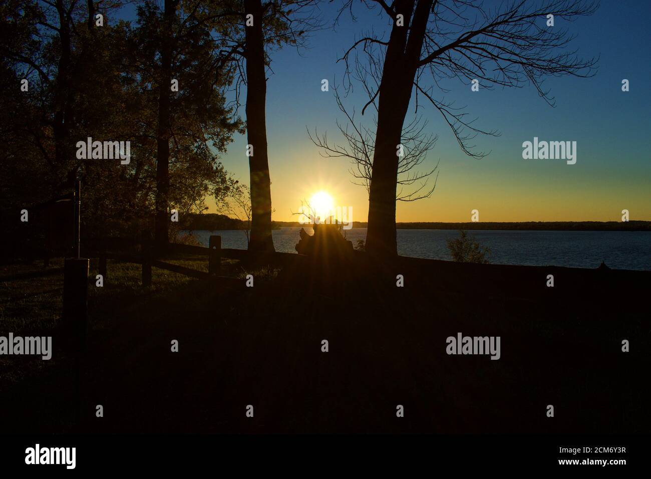 Sun setting over Belmont Bay with the silhouette of trees and cliff ...