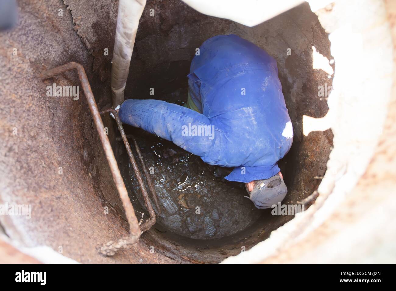 Worker cleans the sewer hatch.A worker cleans a sewer hatch. A man in ...