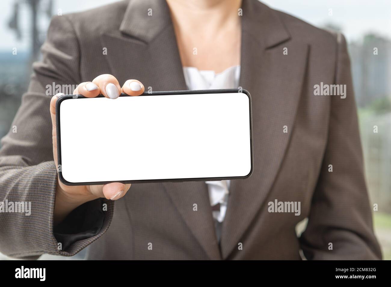 Woman's hand shows mobile smartphone with white screen in horizontal ...