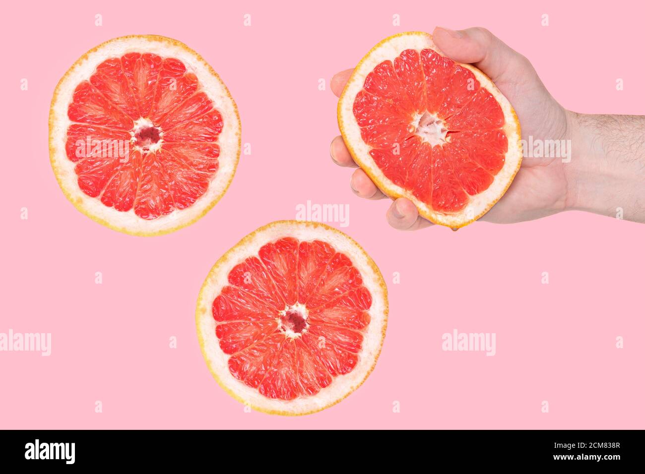 male hand holding grapefruit on pink background. People vivid lifestyle ...