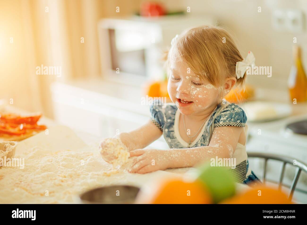 little cute girl is learning how to make a cake, in home kitchen ...