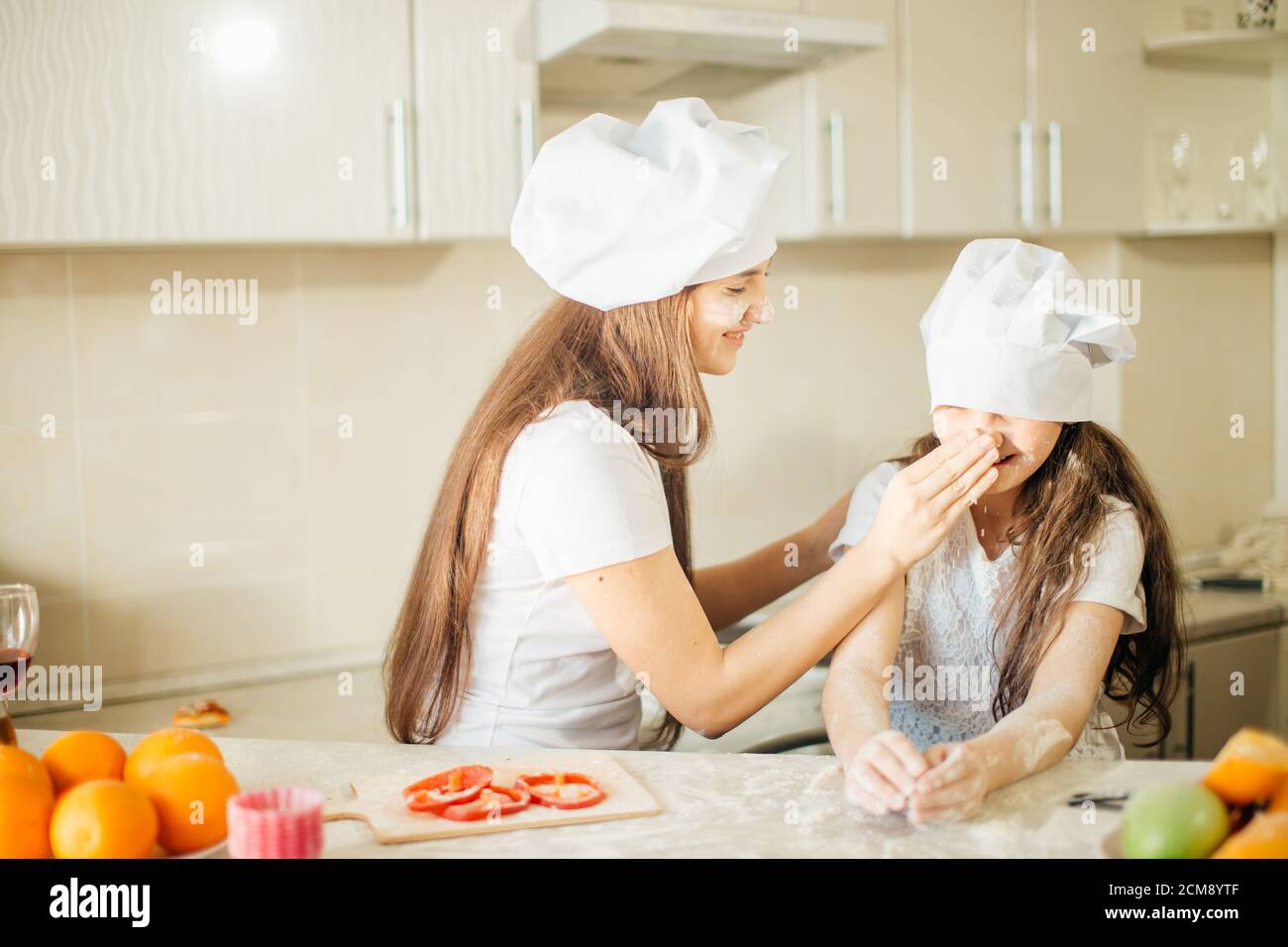 two sisters cooking with her mother in the kitchen. Infant Chef Concept ...