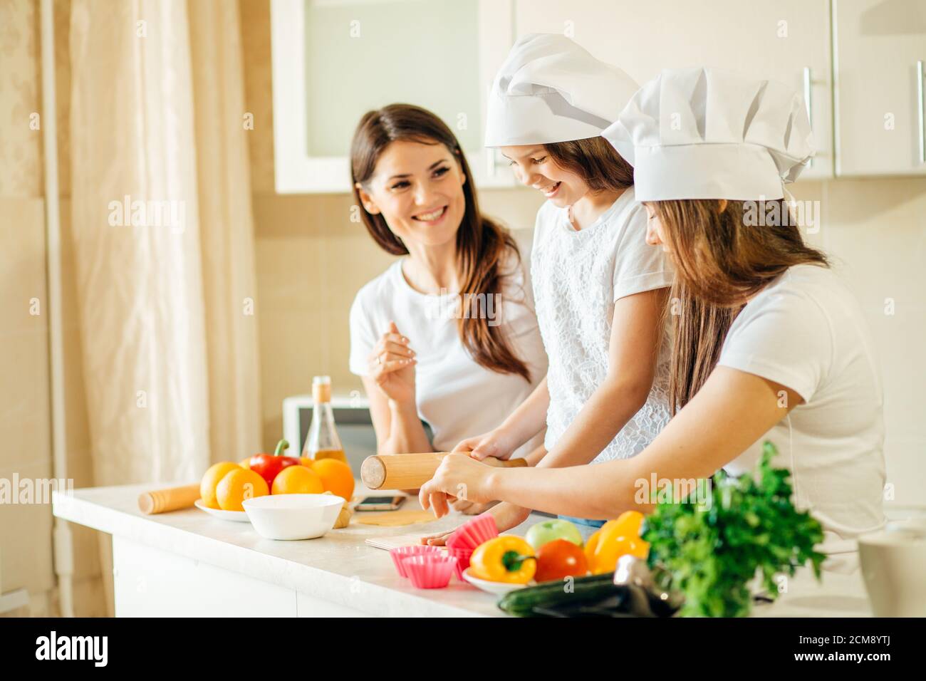 two sisters cooking with her mother in the kitchen. Infant Chef Concept ...