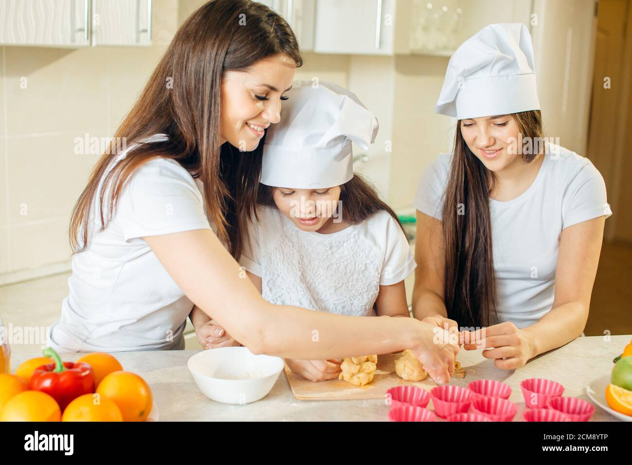 two sisters cooking with her mother in the kitchen. Infant Chef Concept ...