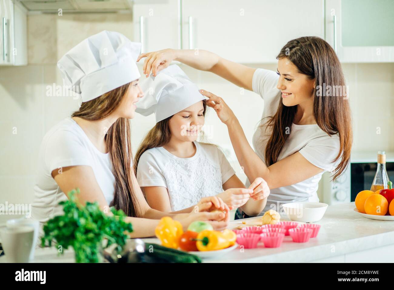 two sisters cooking with her mother in the kitchen. Infant Chef Concept ...