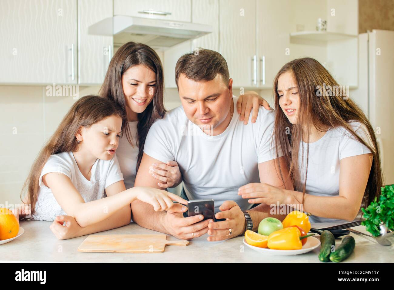 family using cell phone while cooking at kitchen Stock Photo - Alamy
