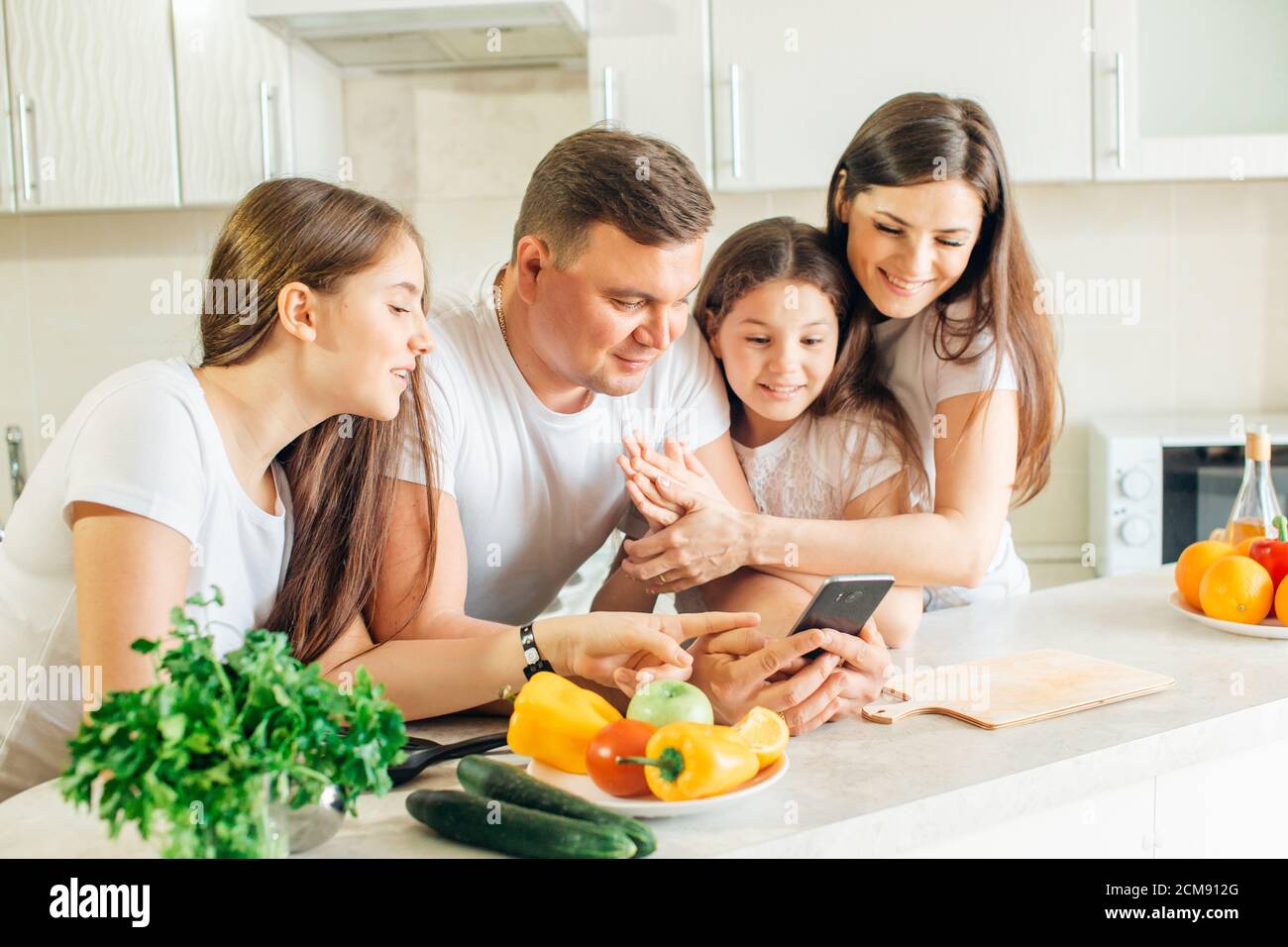 family using cell phone while cooking at kitchen Stock Photo - Alamy