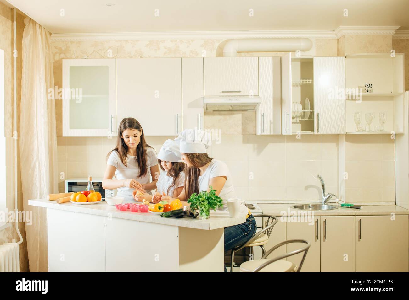 two sisters cooking with her mother in the kitchen. Infant Chef Concept ...