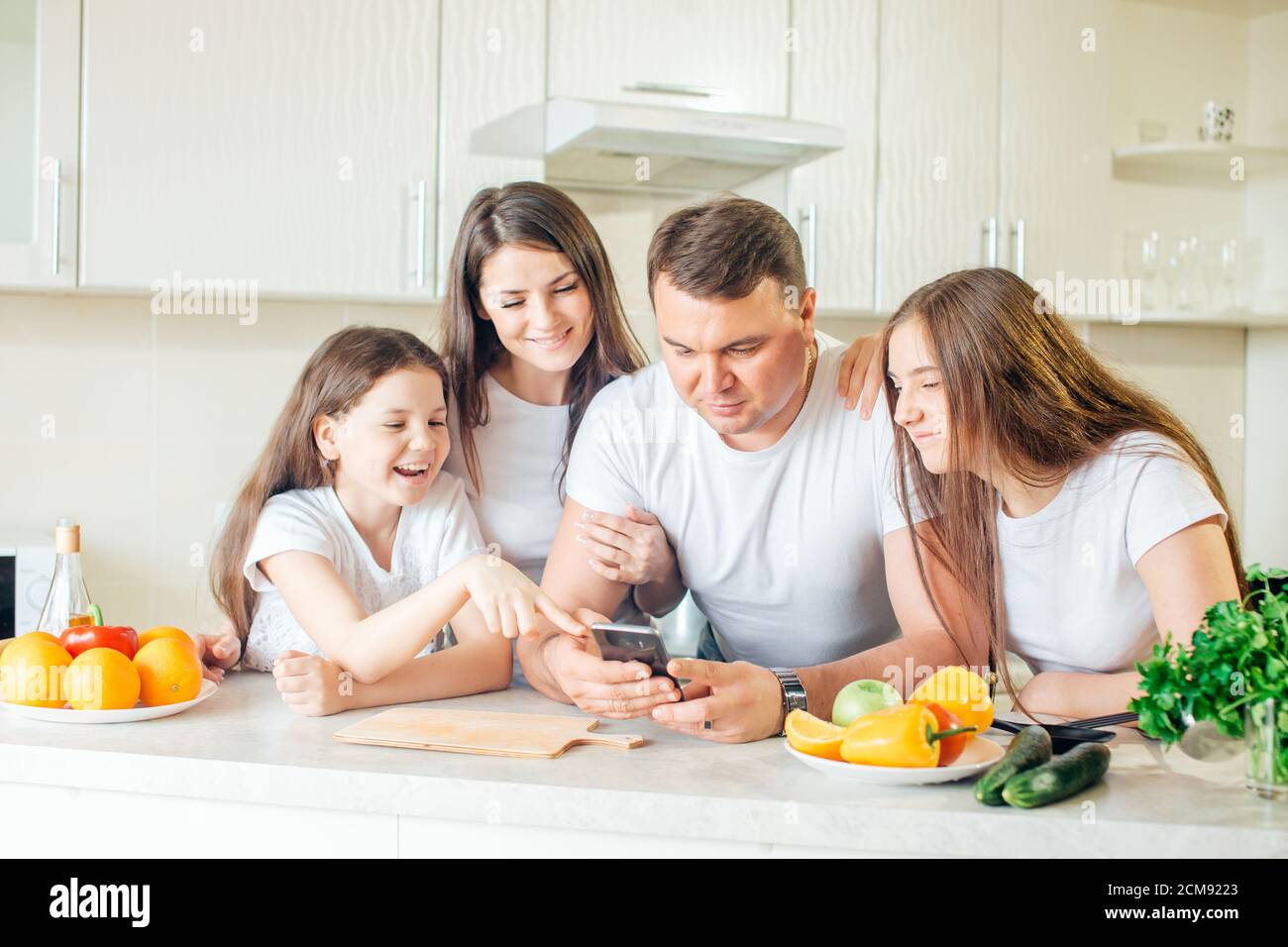 family using cell phone while cooking at kitchen Stock Photo - Alamy