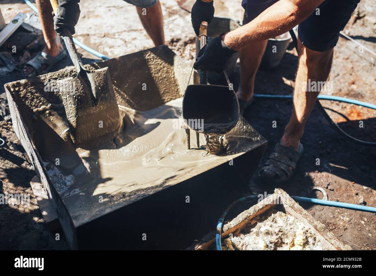 Workers work with cement mortar, loading the hopper bucket with mortar ...